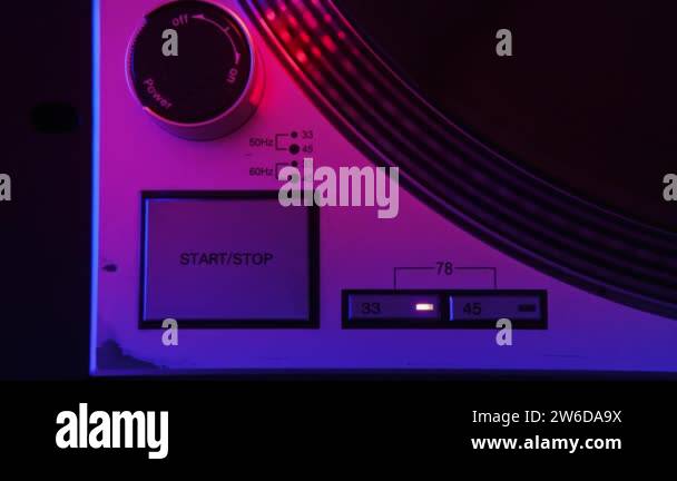 Man starting record player, pushing start button. Neon red and blue ...