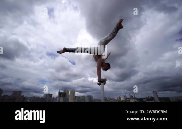 Flexible male circus Artist turning and keep balance by one hand on the ...