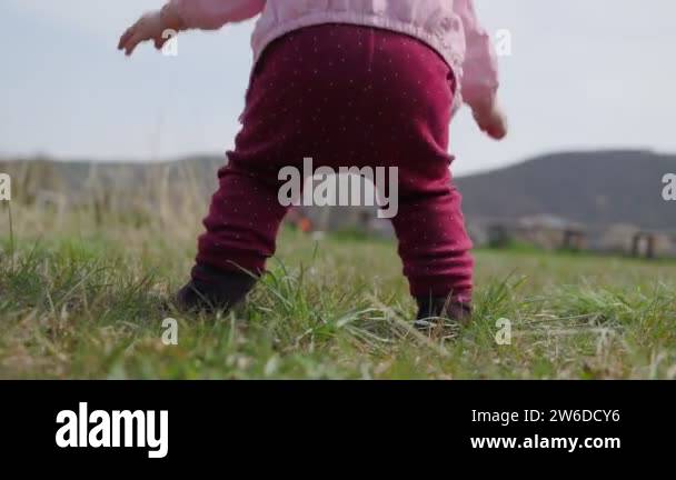 Baby learns to walk by squatting on the grass, grabbing the ground with ...