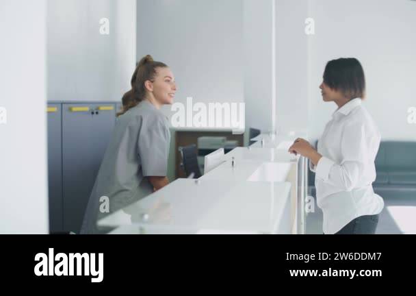 Hospital reception, a nurse registers an young woman patient for a ...
