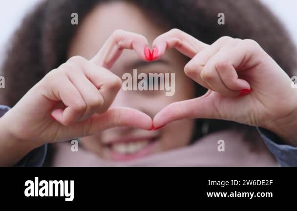 Head shot close up smiling kind afro woman showing heart symbol to ...