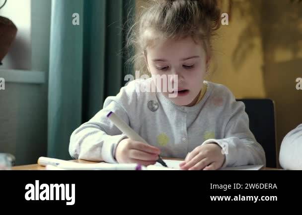 Little preschool cute girl enthusiastically draws with colored pencils ...