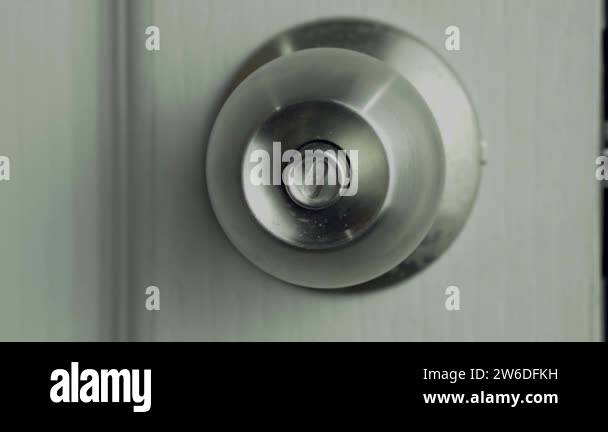 Man's hand is reaching, press the button in the middle of the doorknob ...