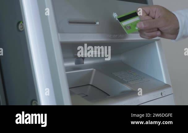 Male hand attaching the card to the ATM machine, withdrawing money from ...