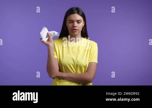 Woman sneezes into tissue. Isolated girl on violet studio background ...