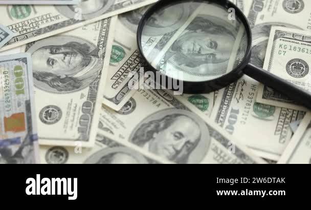 Magnifying glass lying on lot of paper dollar bills closeup 4k movie ...