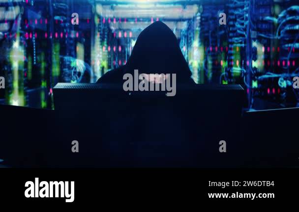 Male hacker typing on keyboard in server room, hacking into system ...
