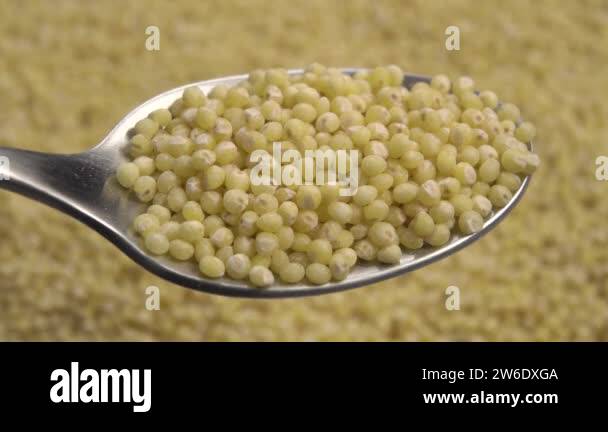 A spoonful of raw millet over a rotating heap of cereal in blur. Macro ...