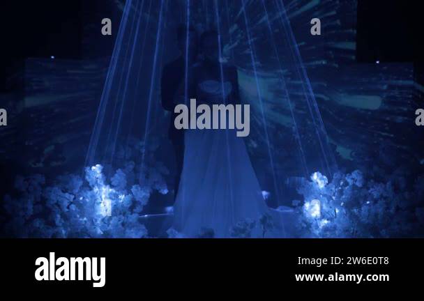 A young couple stands in a circle of laser projection, on their ...