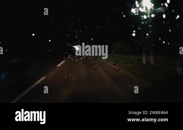 Driving at night. Raindrops on the windshield of the car. Asphalt road ...