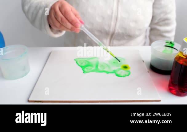 woman applies green paint with a pipette, inflates it, abstract spots ...