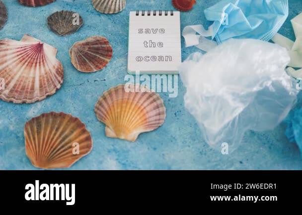save the ocean text on blue background with sea shells and plastic ...