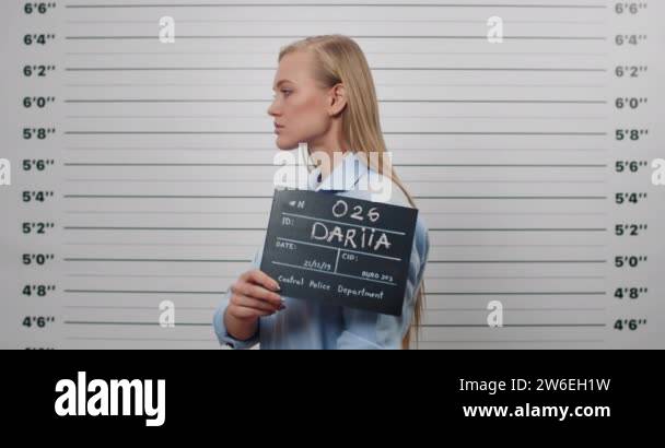 Mugshot of attractive woman holding sign for photo in police department ...