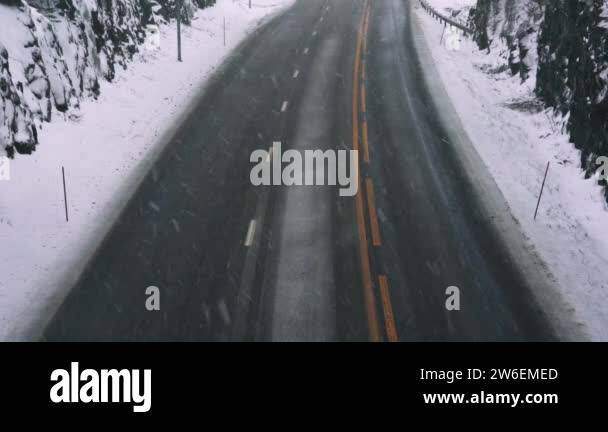 Snow falling on a highway with no traffic on a cold winters day ...