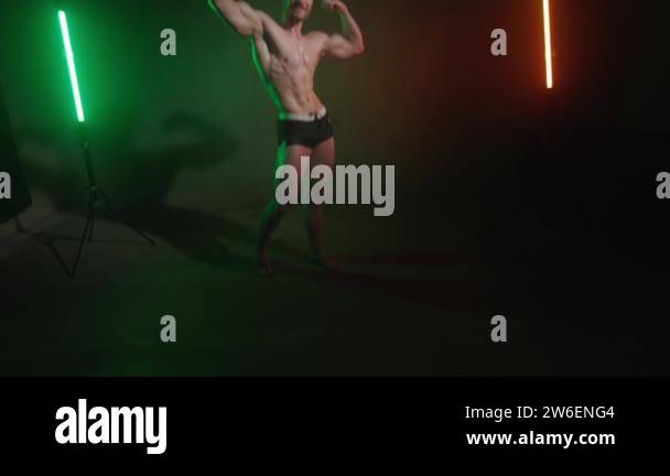 A sportsman with a bare body is posing and showing biceps. The camera ...