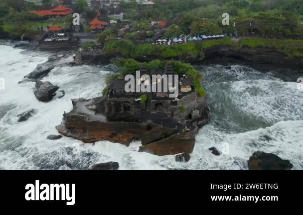 Tilting aerial shot flying away from empty Tanah Lot temple during ...