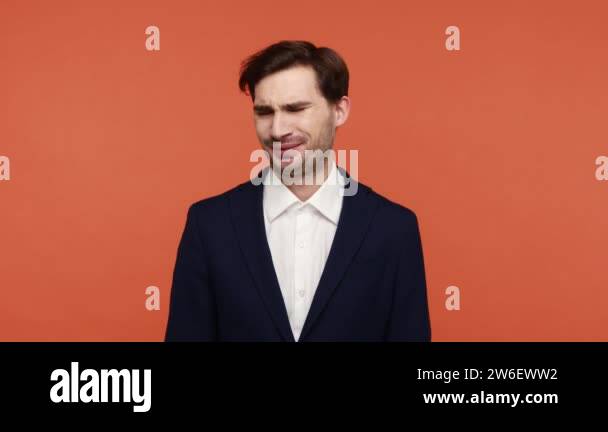 Young bearded businessman in black suit grabbing nose with fingers, frowning face with disgust ...