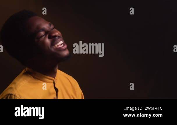 Stylish African American man in yellow shirt emotionally sings a song ...