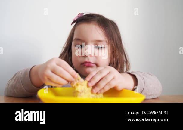 Toddler girl eating bread or pie at home with her hands. Hungry kid ...