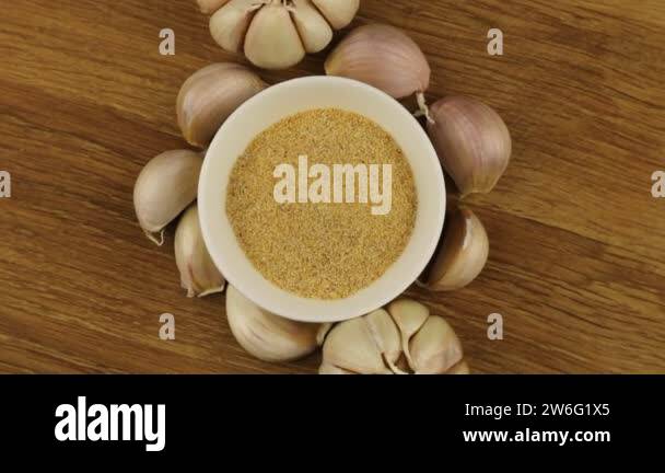Ground garlic powder on the saucer and heads of garlic around rotates ...