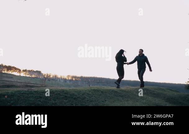 Wide frame with a mature couple who walk happily and hold hands smiling ...