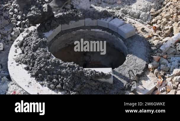 Construction worker installation of sewerage a sewer manhole on septic ...