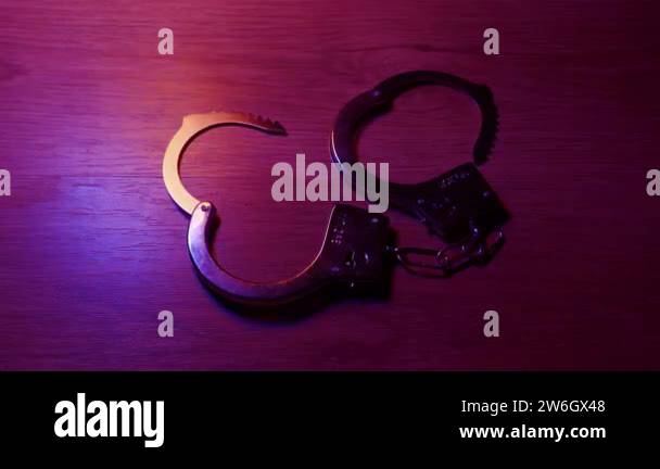 Police handcuffs are on the wooden table. The police lights are ...