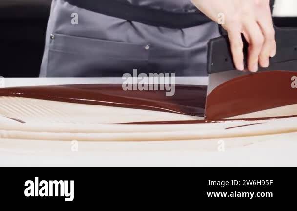 Confectioner chocolate tempering. Woman chef in uniform tempering ...