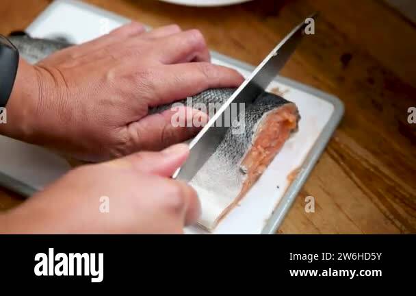 Man cuttings red fish on plastic board. Chef cutting salmon in the ...