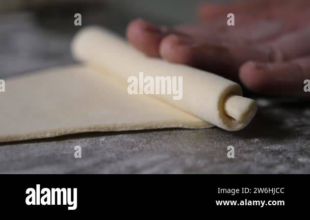 Worker`s hand twisting up a dought sheet to make a croissant at a ...