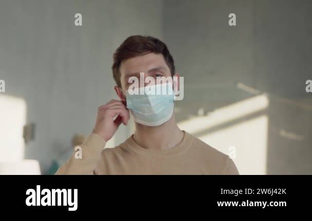 Young man taking off his blue medical mask. Young smiling guy taking ...