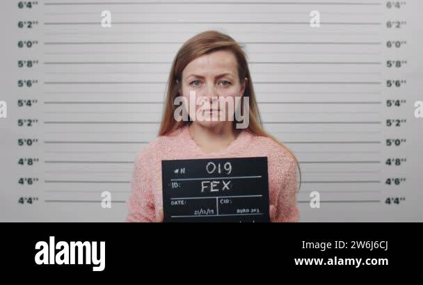 Mugshot of young arrested woman holding sign for photo in police ...