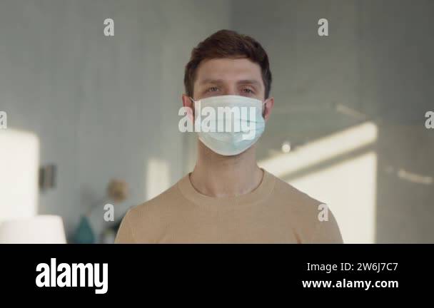 Young man taking off his blue medical mask. Young smiling guy taking ...