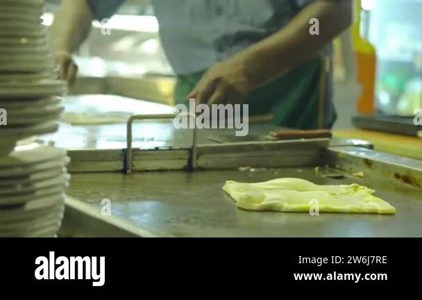 Indian man cooking roti canai at a restaurant in Kuala lumpur - Side ...
