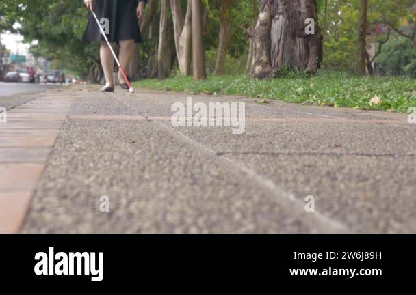 Defocused disabled blind person woman walking on sidewalk with a long ...