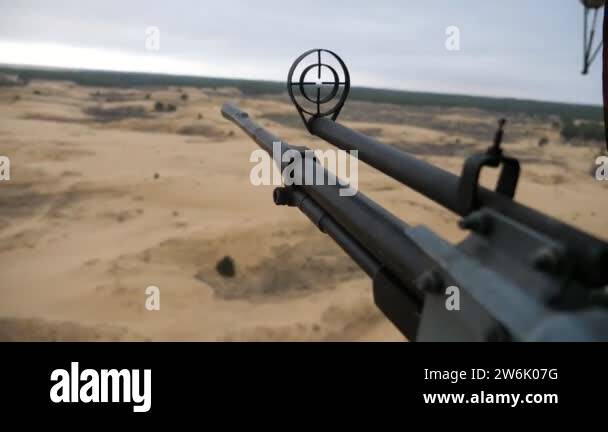 Air machine gun with a cartridge tape is aimed at desert objects from a ...