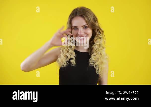 Young cute smiling girl showing OK sign isolated on yellow background ...