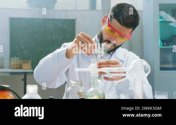Concentrated scientist man in his chemical laboratory take some chemical liquid to make a ...