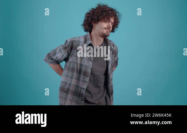 The stressed young man painfully puts his hands behind his back ...