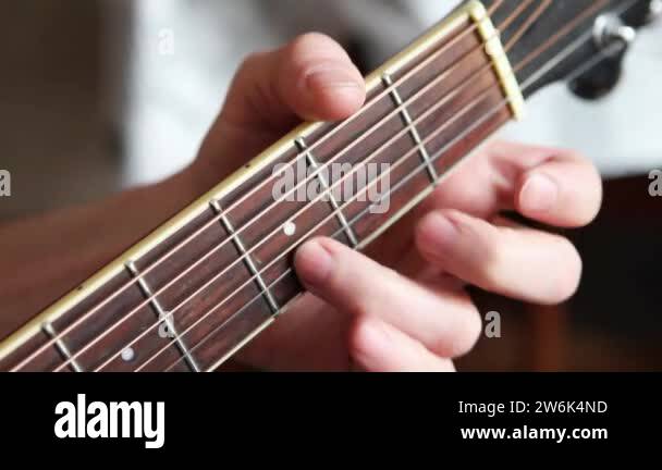 A man's hand on the fretboard of a guitar runs his fingers through the ...
