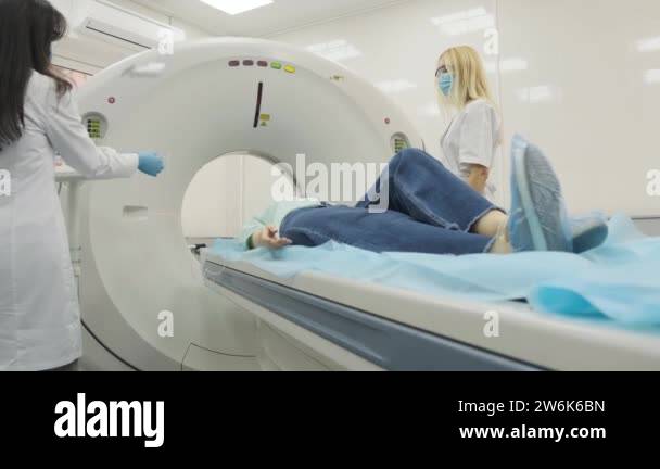 Female patient is undergoing CT or MRI scan under supervision of two ...