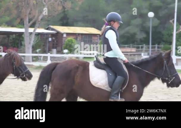 Happy teen girls jockeys in helmets riding obedient horses on sandy ...