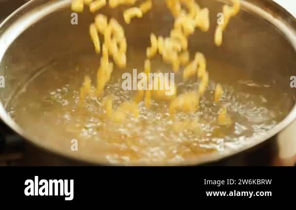 pasta falling into clean boiling water in stainless steel pot - slo-mo ...