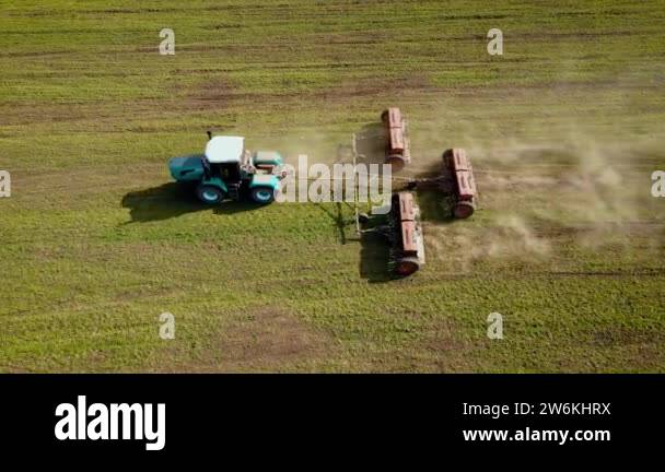 Modern powerful tractor spreading artificial fertilizers in field with ...