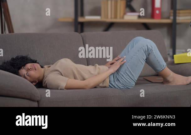 Overburdened exhausted African American woman lying on couch holding ...