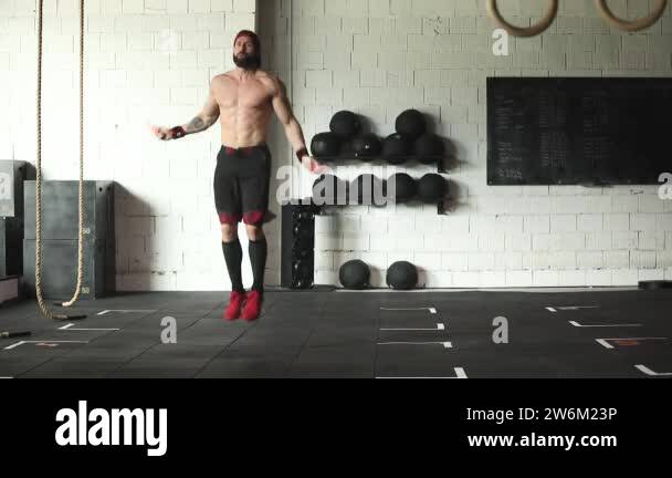 Muscular shirtless male athlete jumping rope during cardio training in ...