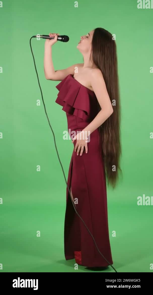 Portrait of beautiful young woman sings a song into a microphone. Model ...