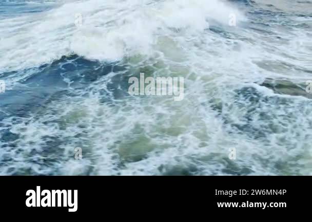 Tons of water turn into large waves behind the stern of a large ship ...