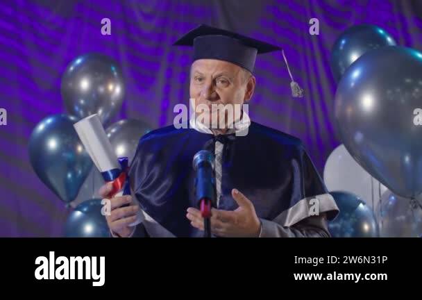male rector in academic hat and mantle congratulates students with ...