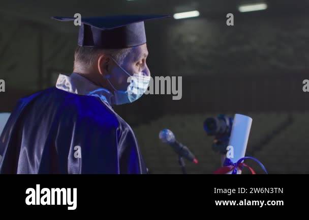 university lecturer in academic clothes and hat is presenting diplomas ...